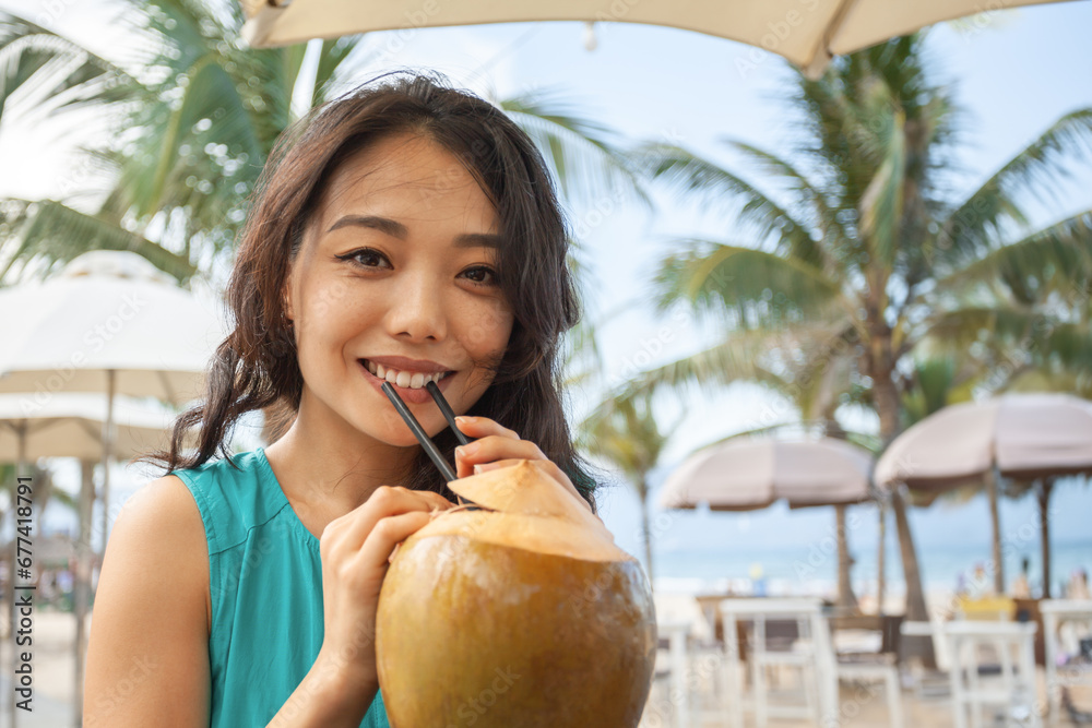 Happy Asian girl drinking fresh coconut water juice on the beach at her ...