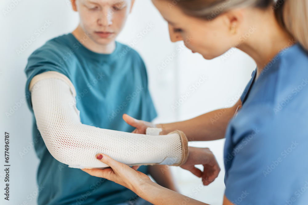 Doctor checking the orthopedic cast, brace on a teenage patient's ...