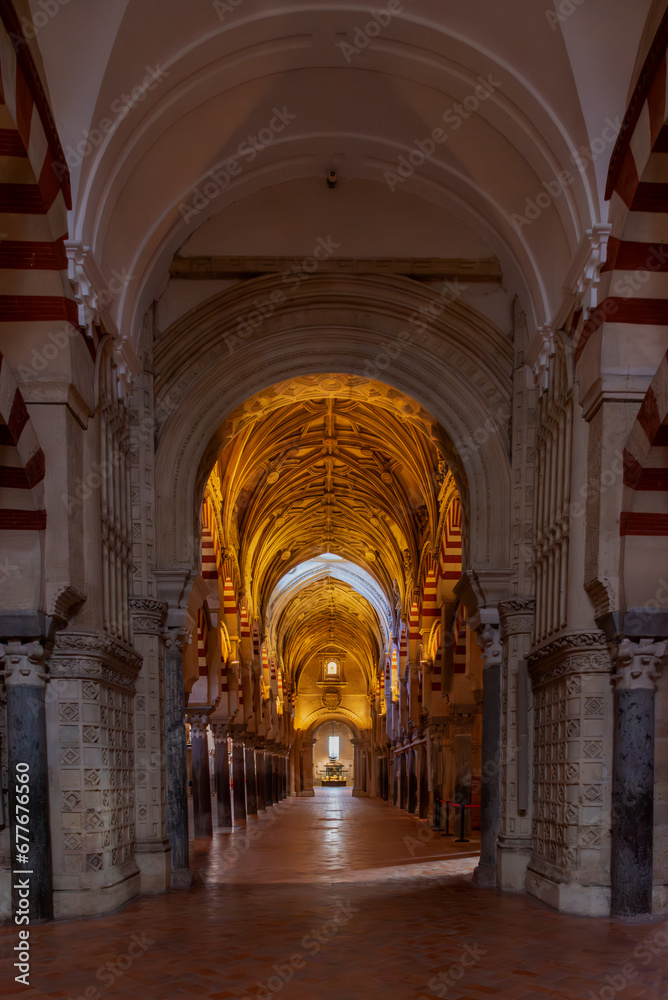 Corridor between pillars and decorated arches with views of a chapel in ...