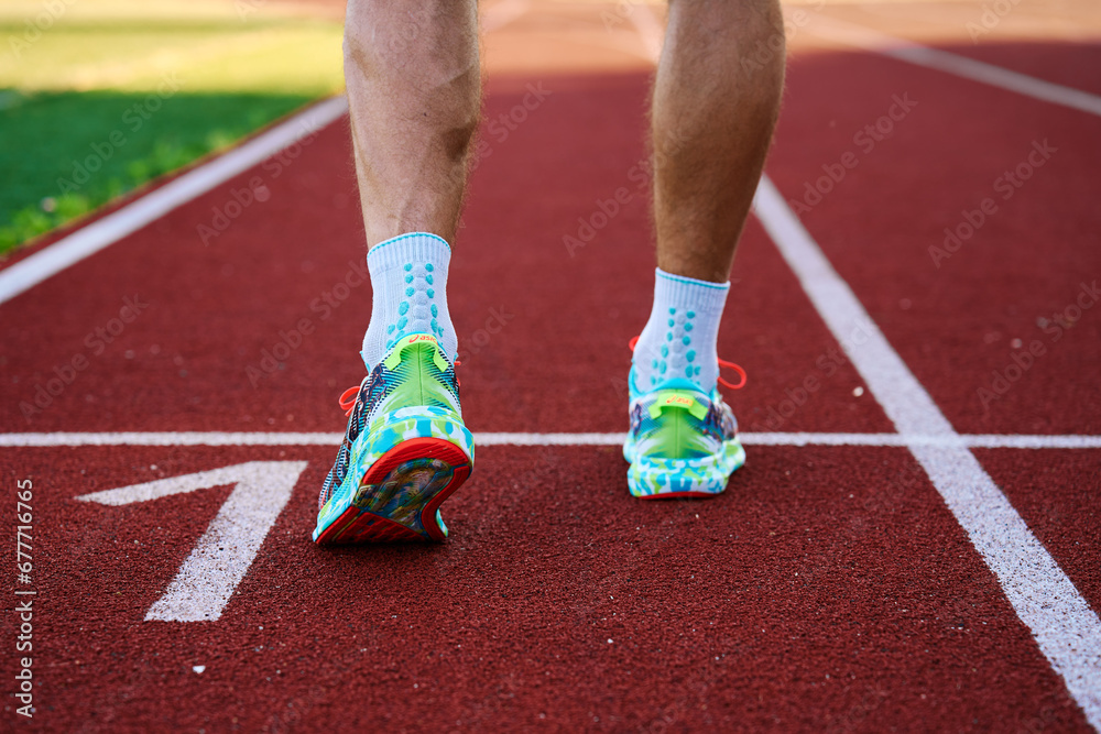 Male sprinter wearing Asics Noosa Tri 13 at stadium track preparing to ...