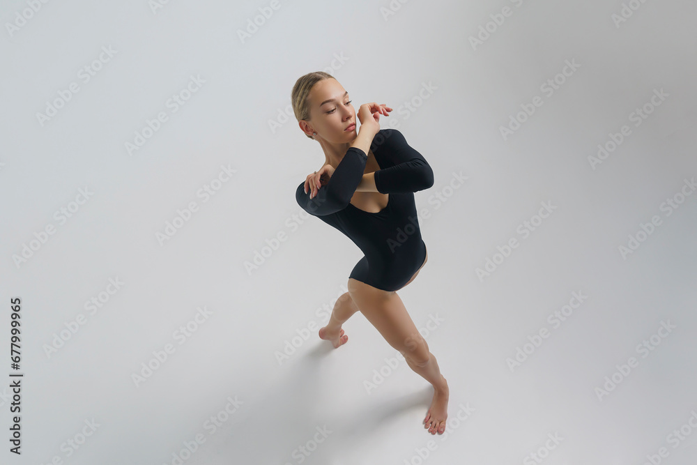 portrait of a young ballerina in a black bodysuit shows ballet steps ...