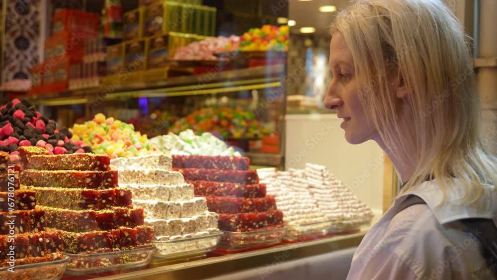 Female tourist looking at turkish sweets through shop glass or window ...