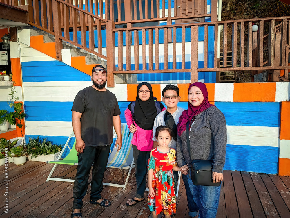 Malay Muslim family taking photo while traveling on vacation at a beach ...