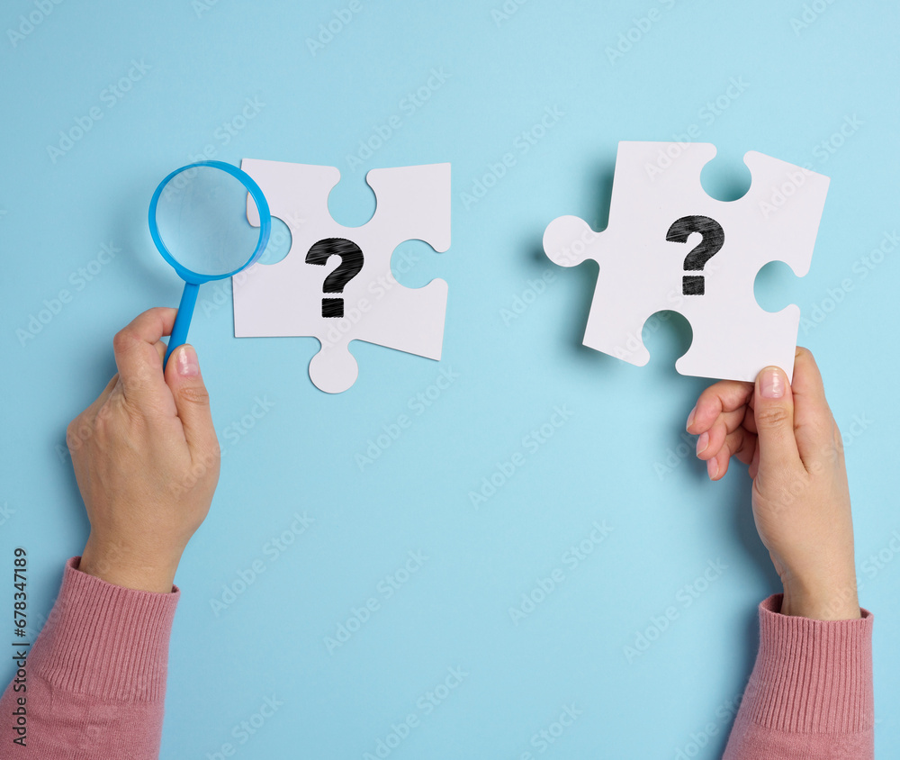 White puzzles with a question mark and a female hand holding a plastic ...