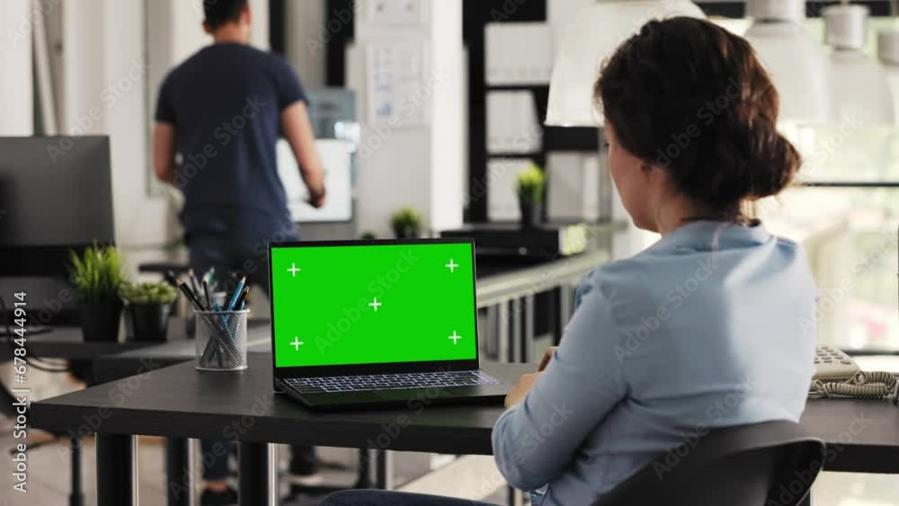 Employee checks greenscreen on laptop, looking at isolated copyspace ...