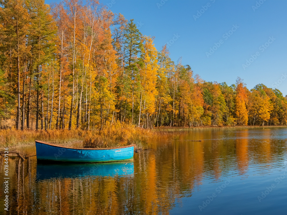 Une vieille barque sur un lac entouré de grands arbres aux couleurs de ...