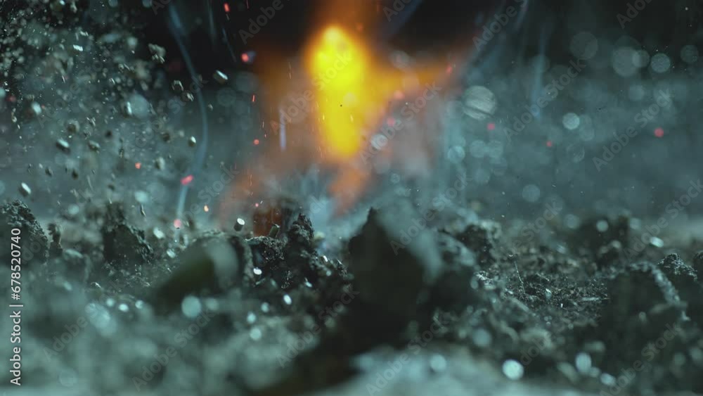 As a flam burns a pile of crumbled charcoal is tossed in the air and ...