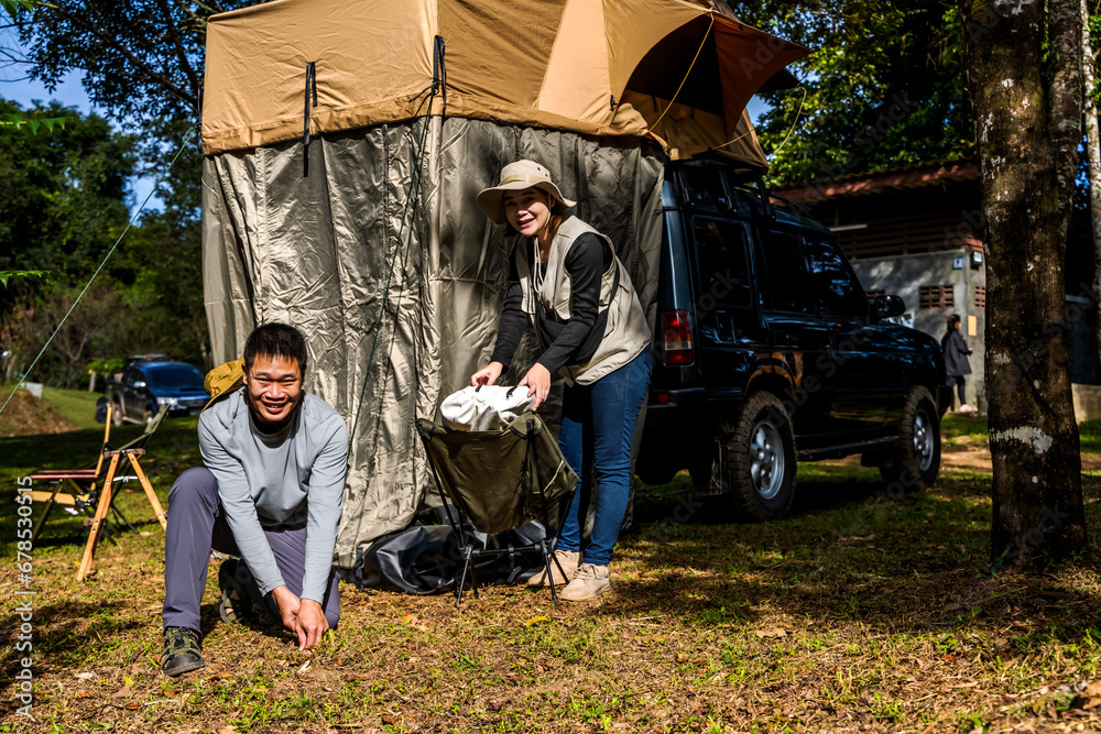 Adventurous Asian couples helping each other pitch a tent for camping ...