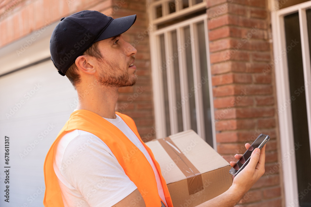 Delivery man checking the customer home address on his mobile phone ...