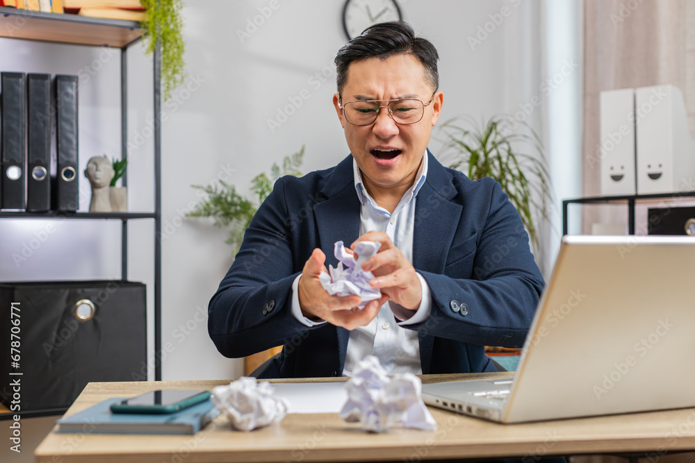 Angry furious Asian businessman working at office throwing crumpled ...