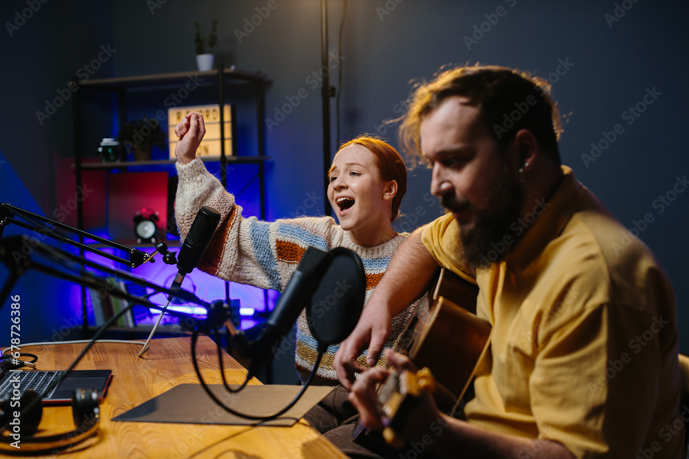 A cheerful couple of radio presenters perform a song on air. A man and ...
