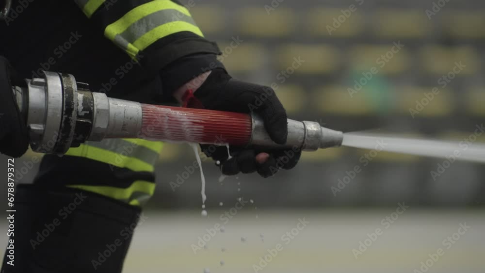 An up-close shot captures a fire hose with a powerful stream of water ...