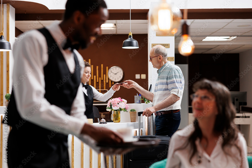 Caucasian receptionist helps retired old man with hotel check-in ... Caucasian receptionist helps retired old man with hotel check-in ...