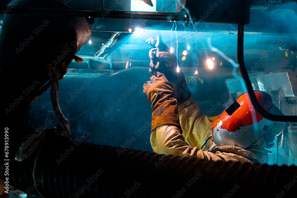 man working under a train using a welder Stock Photo | Adobe Stock