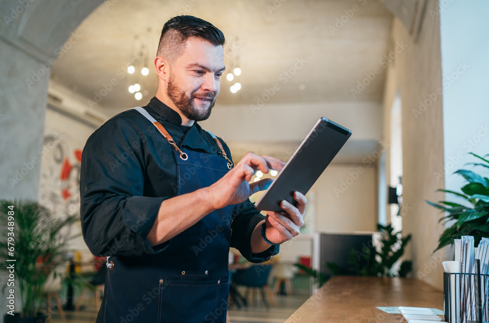 Smiling small business owner dressed in a black chef uniform with an ...