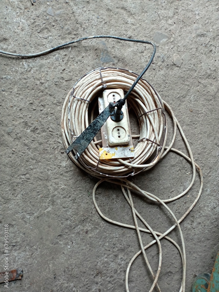Old white dirty electrical extension cord on concrete floor in garage ...