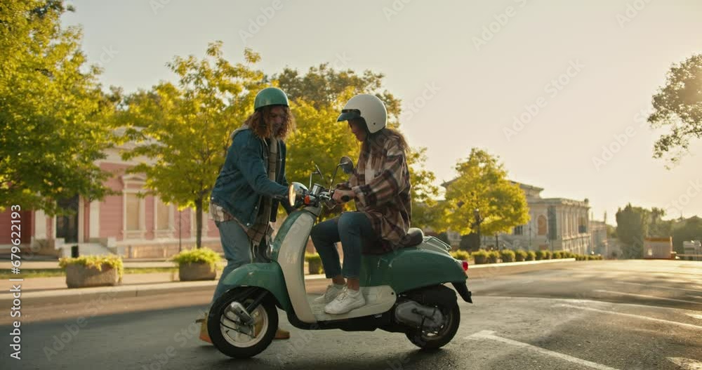 A guy with curly hair in denim helps a girl move while riding a moped ...