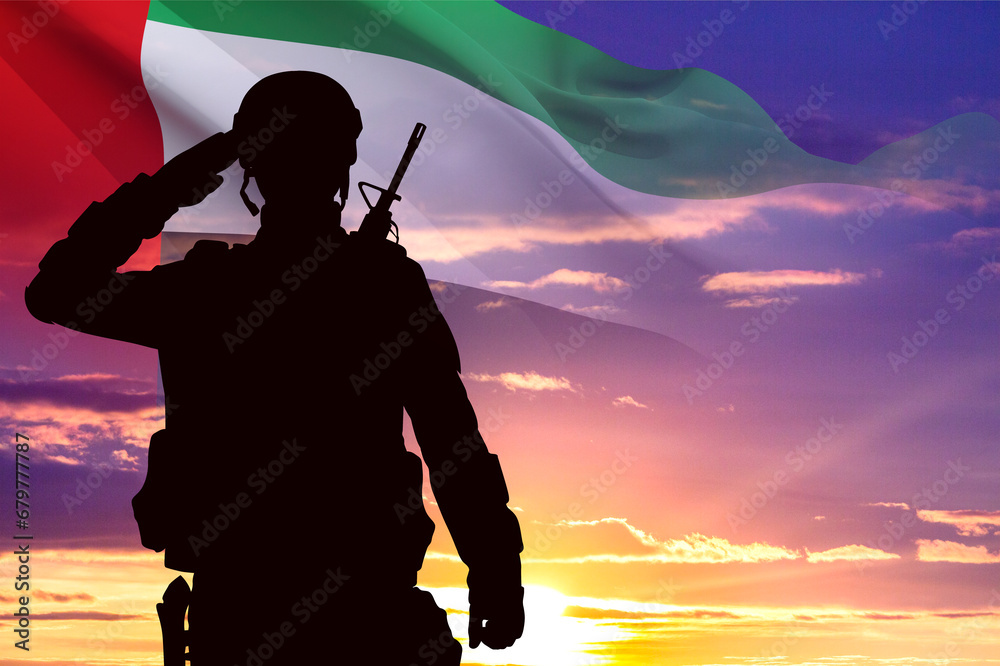 Silhouette of saluting soldier with the flag of UAE against the sunset ...