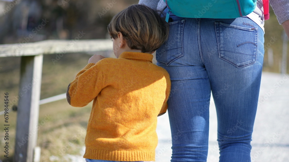 Back of child holding hands with mom walks in outdoor pathway forward ...