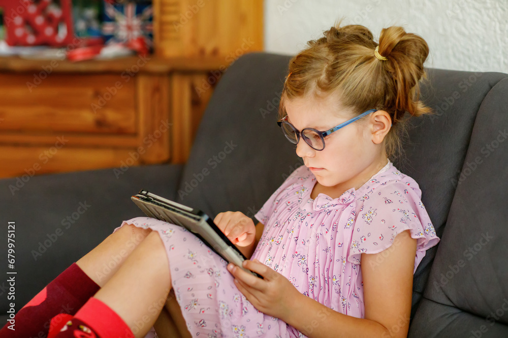 Positive little girl, holding tablet computer in her hands. Preschool ...