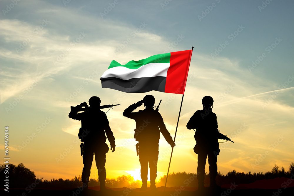Silhouettes of soldiers with the flag of UAE against the sunset. Armed ...