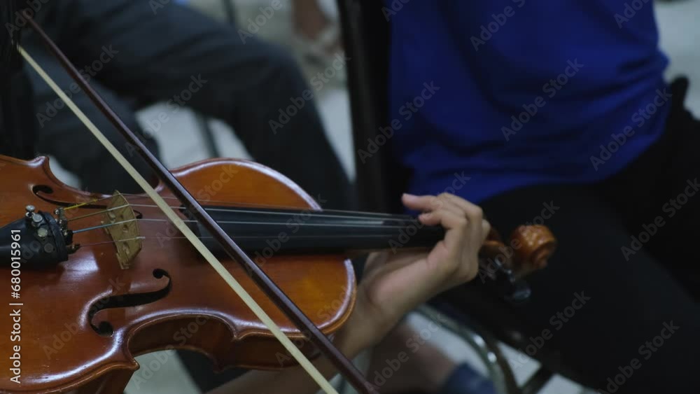 Hands playing the violin, bowing up and down and the left-hand fingers ...