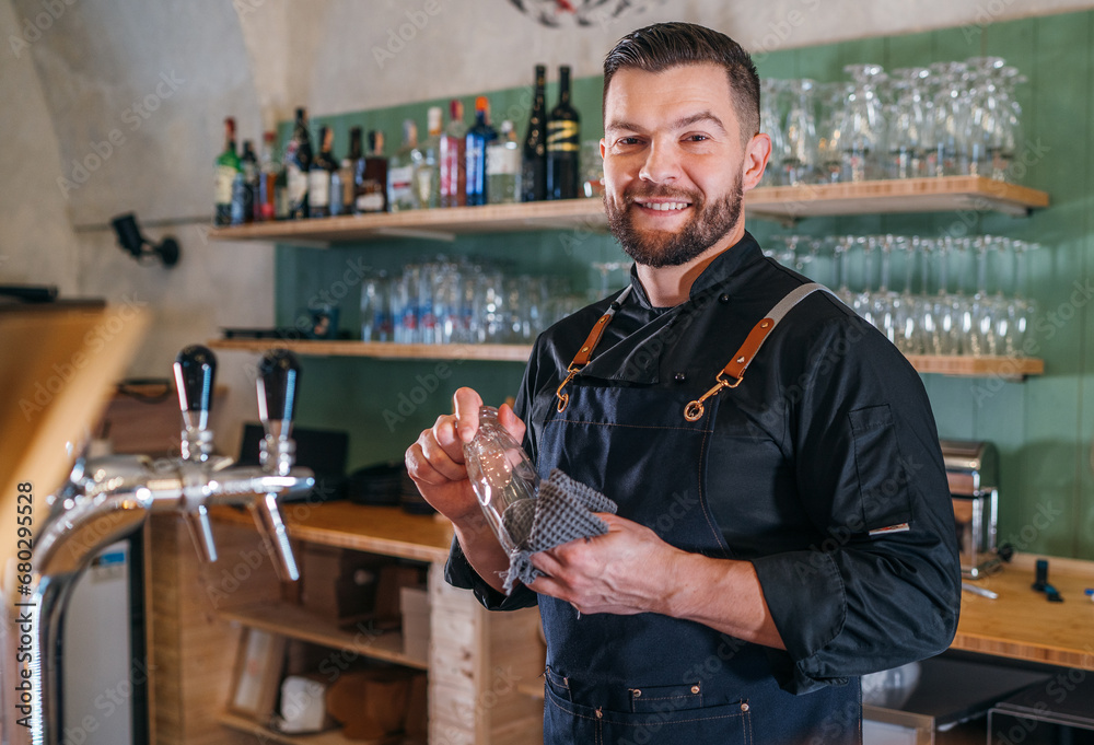 Portrait of happy smiling bearded barman dressed in a black uniform ...