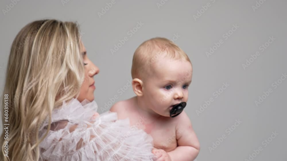 Loving mother in white robe waving her little child. Cute baby with ...