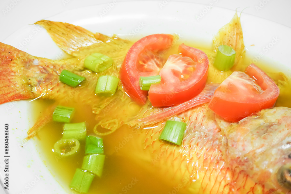 Tilapia fish soup in a bowl with turmeric sauce and spices, using ...