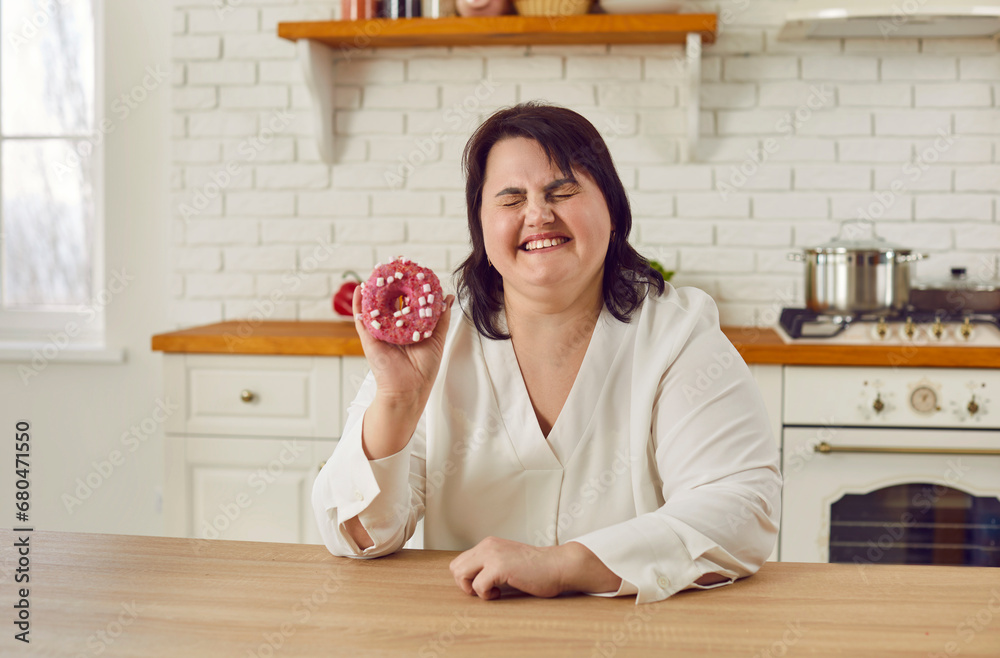 Smiling overweight young woman holding pink glazed donut in her hand ...