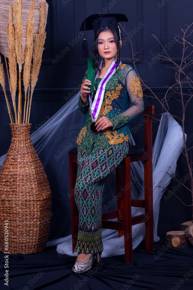 beautiful Asian woman graduating standing in front of a chair smiling ...