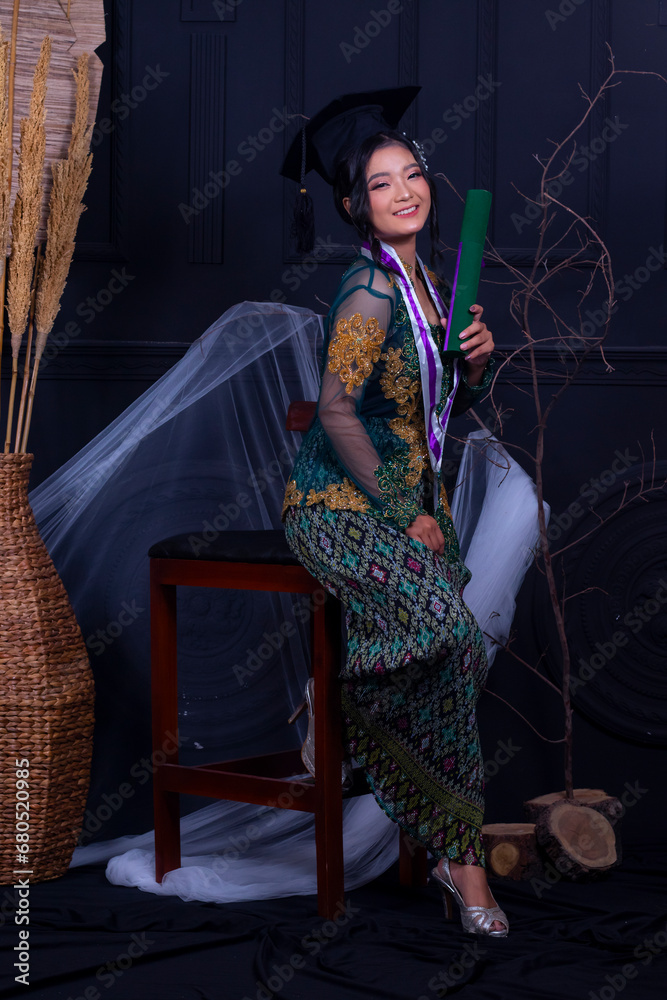 Beautiful exotic Asian woman graduating smiling happily holding diploma ...