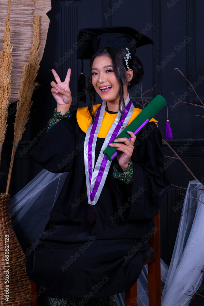 beautiful exotic Asian woman graduating, smiling happily, holding a ...