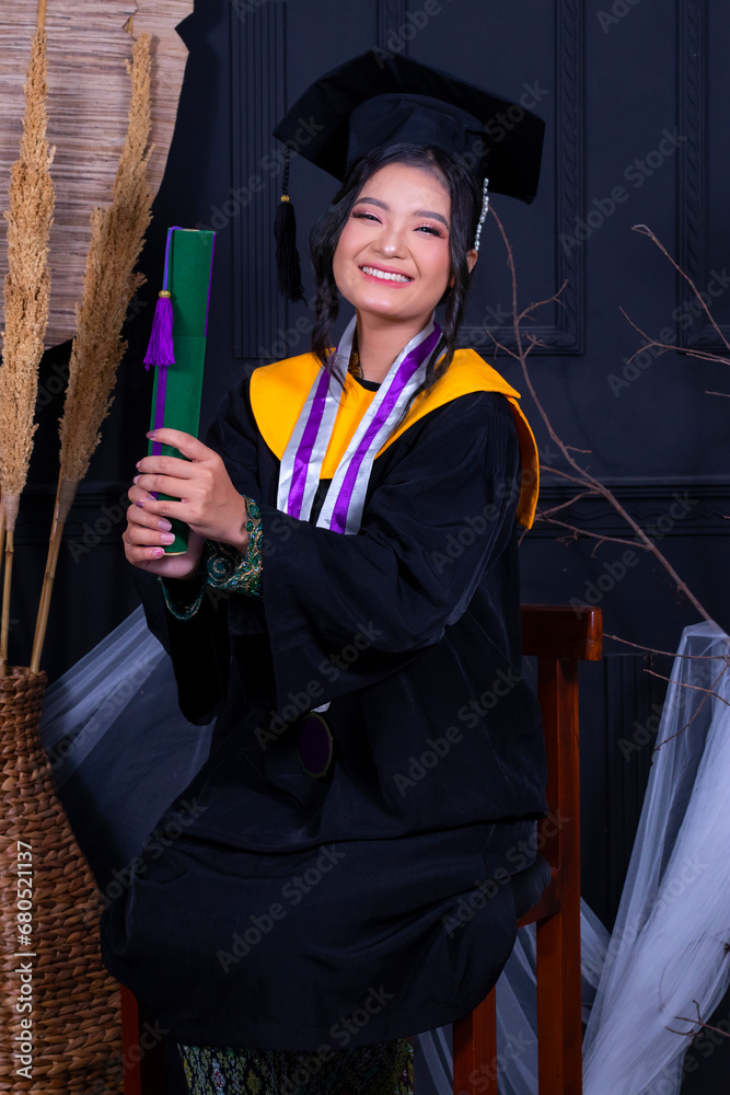 Beautiful exotic Asian girl graduating, smiling happily, hands holding ...