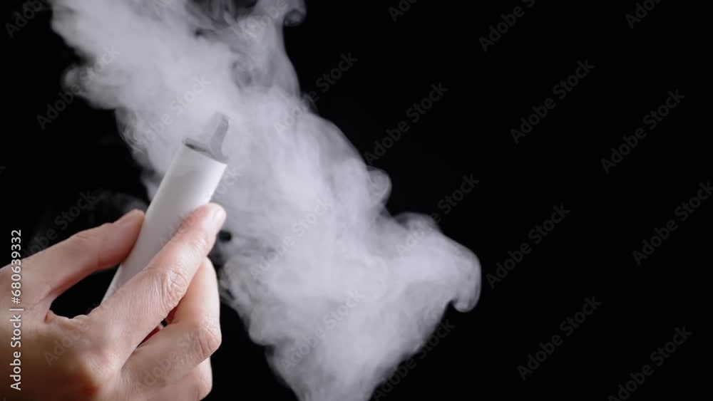 Close up, Smoking a Vape or E-cigarette in a Dark Room on a Black ...