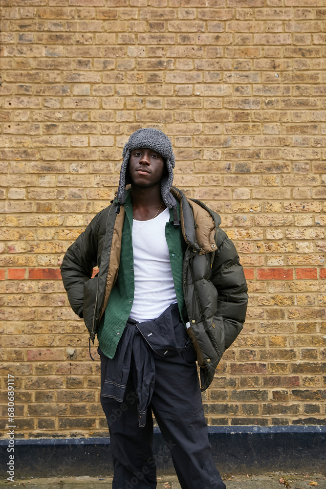 Gen Z black boy with cool winter style posing in front of brick wall ...