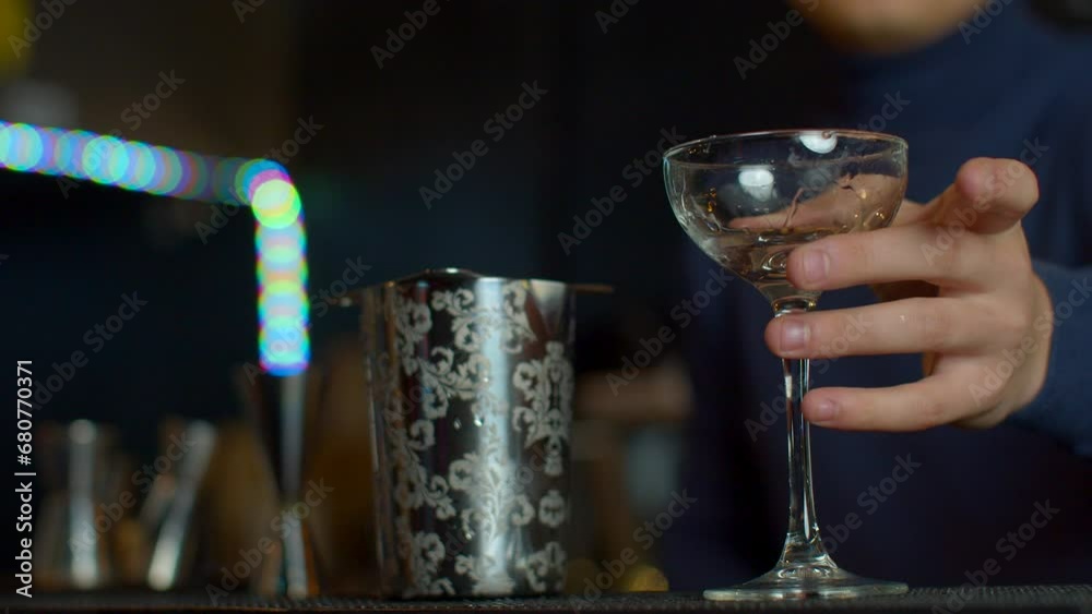 Close up bartender throwing away ice cubes from a small cocktail glass ...