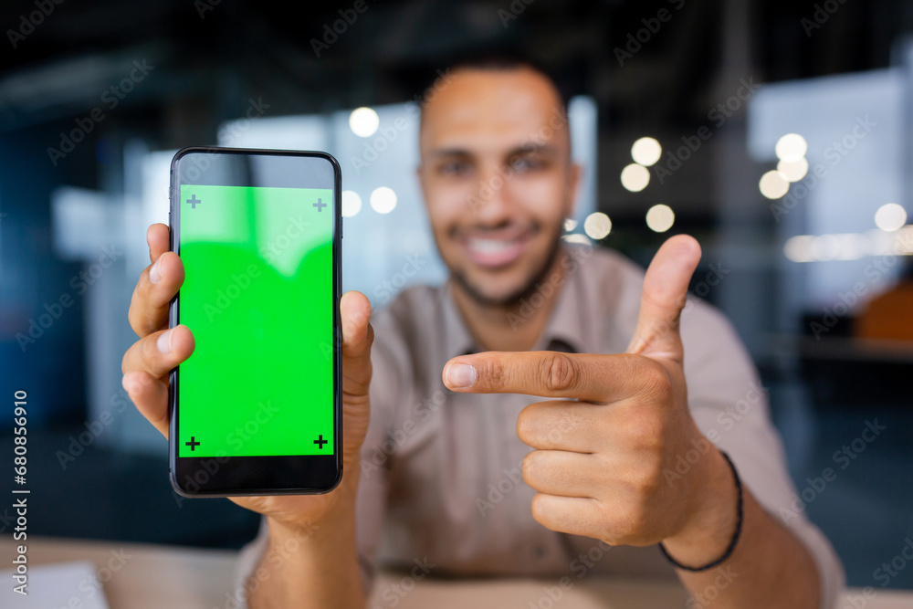 Smiling man holding a phone with a green screen in his hands, showing ...