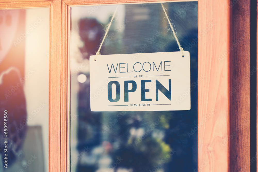 Welcome we're open word on wooden signboard behind transparent mirror ...
