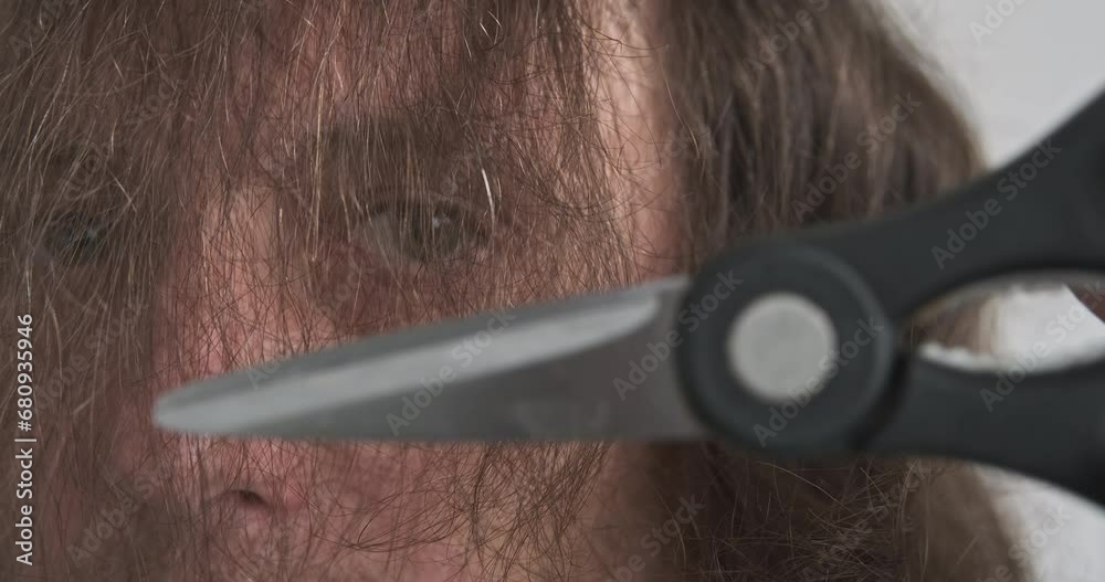 Male face covered with hair. Man cuts with scissors against own eyes ...