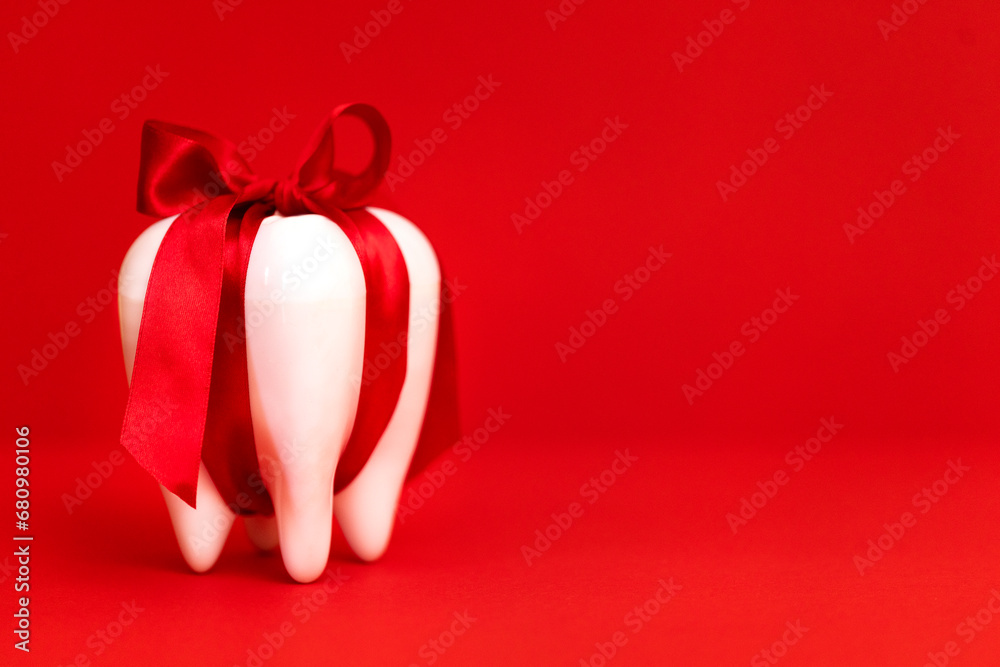 Tooth as a gift. A large white modal molar is tied with a red ribbon ...