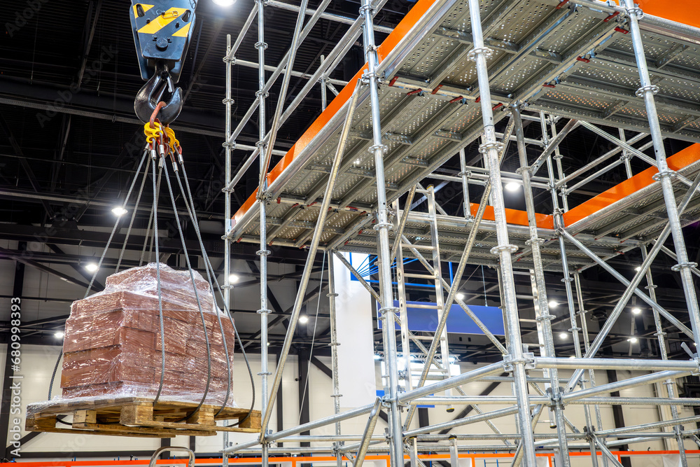 Pallet with cargo is hung on hook of crane. Mezzanine inside industrial ...