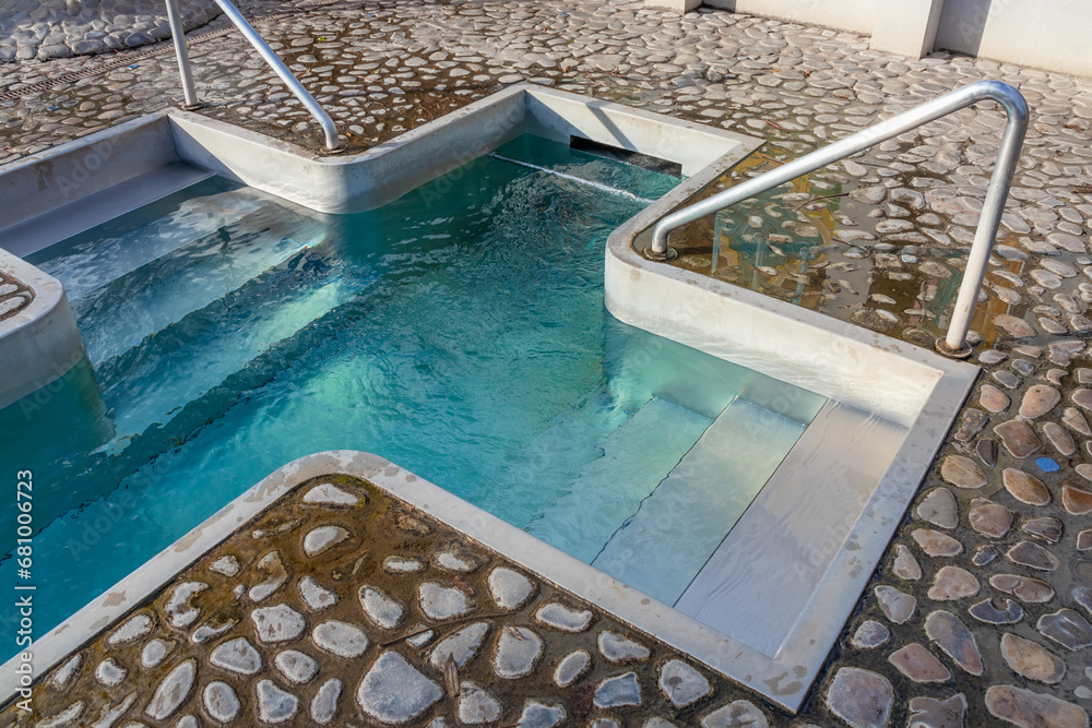 Open air cross-shaped pool with steps and railings filled with water ...