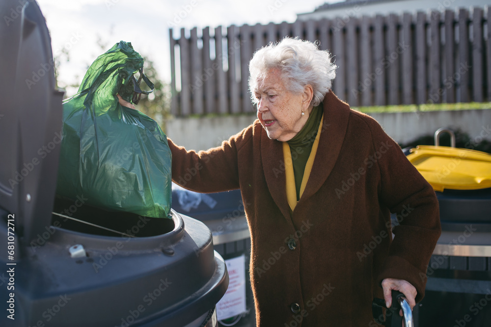 Elderly woman disposing of trash into the garbage can, waste container ...