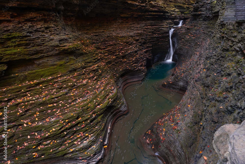 Waterfall in deep limestone gorge surrounded by forest trees during ...