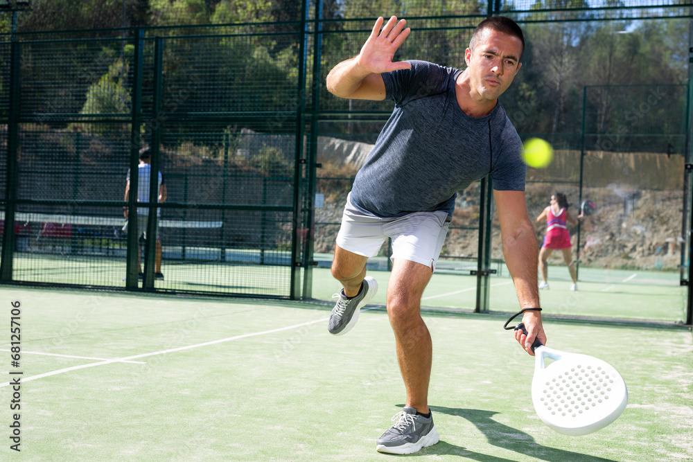 Male padel tennis player training on court. Man using racket to hit ...