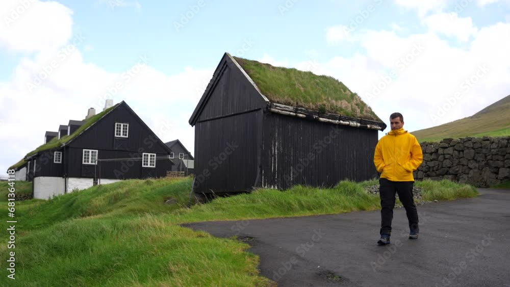 Man in yellow raincoat walks near traditional Faroese houses of ...