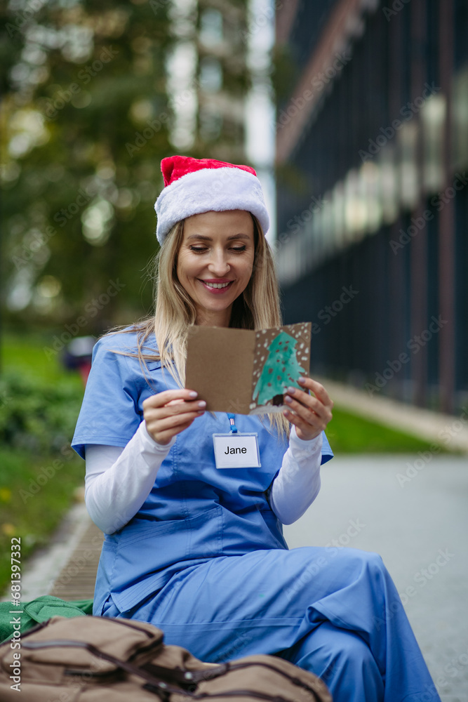 Nurse with christmas hat on head reading christmas card from child ...