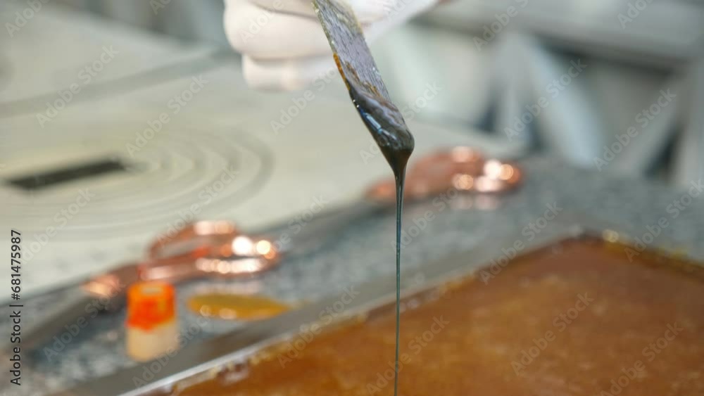 A close-up of a pastry chef pours dye on liquid caramel in a pastry ...