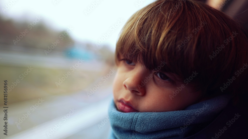 Introspective young boy with scarf, nestled by the train window, lost ...